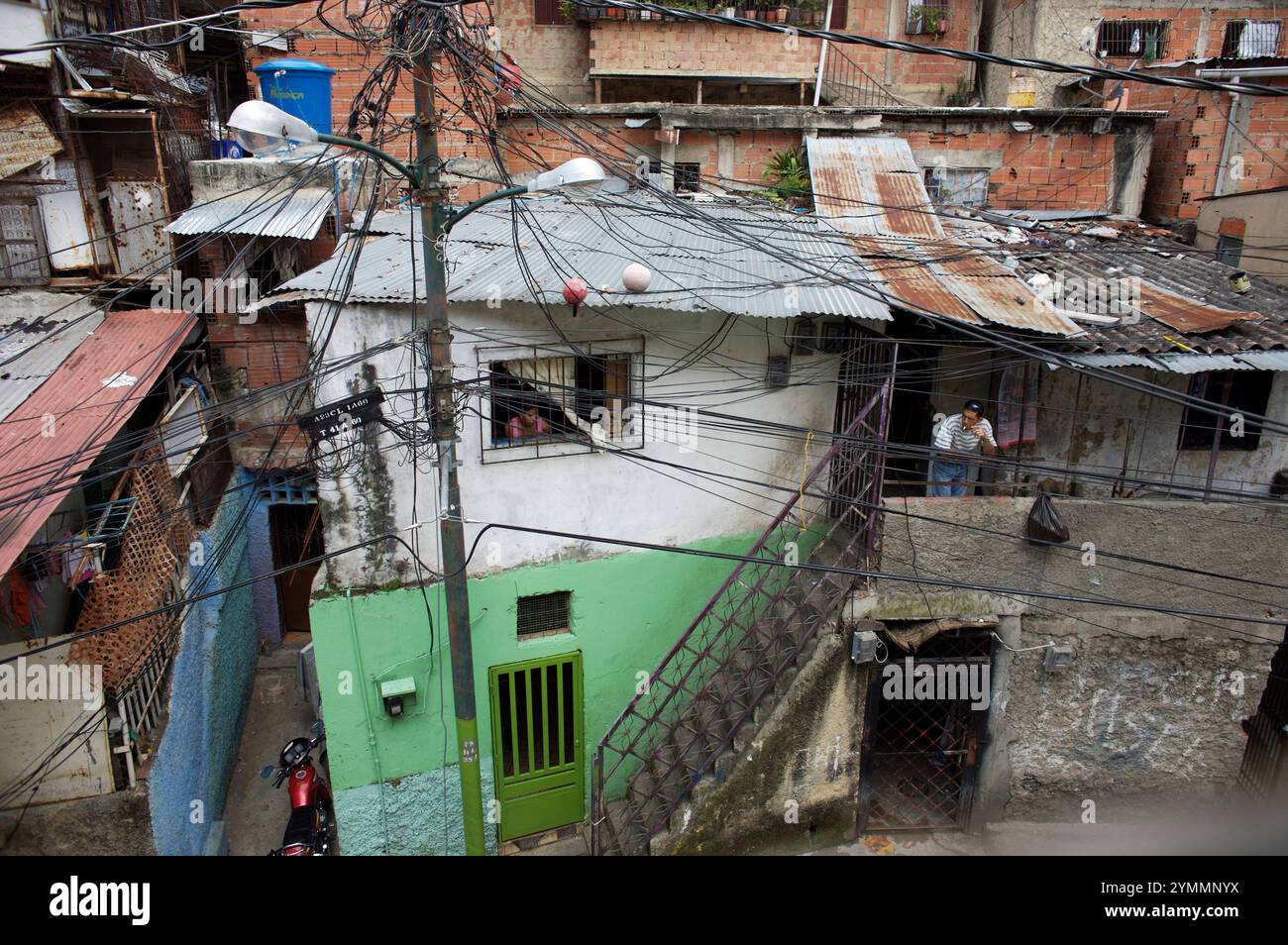 A man has a smoke as he looks out from his cynderblock home in the ...
