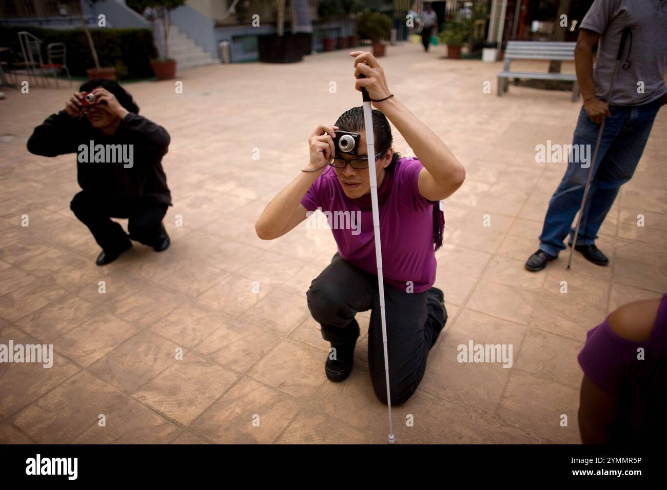 Blind and visually impaired students take pictures as they kneel on the ...
