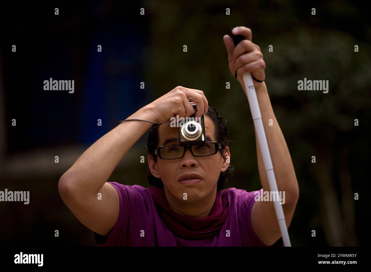 A visually impaired student takes pictures using his cane to support ...