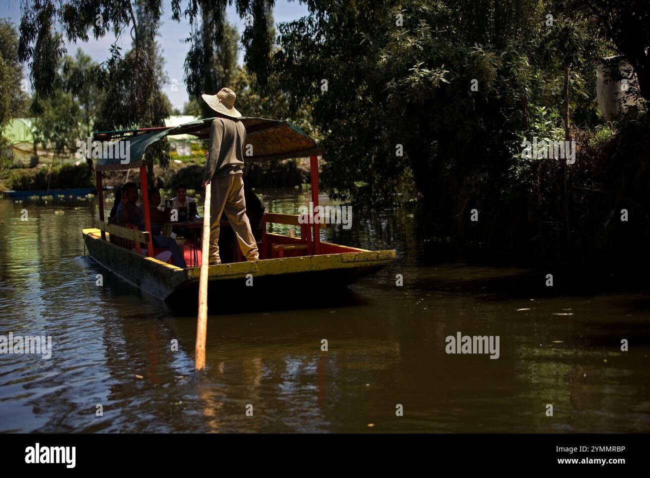 A man rides a boat through the water canals of Xochimilco on the south ...