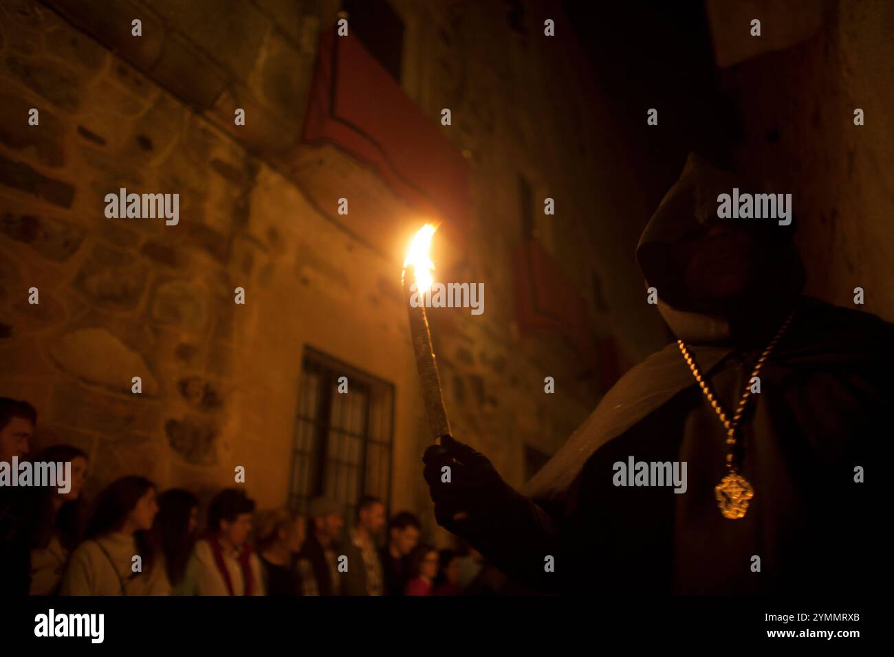 A penitent dressed as a Benedictine monk holds a torch at the ...
