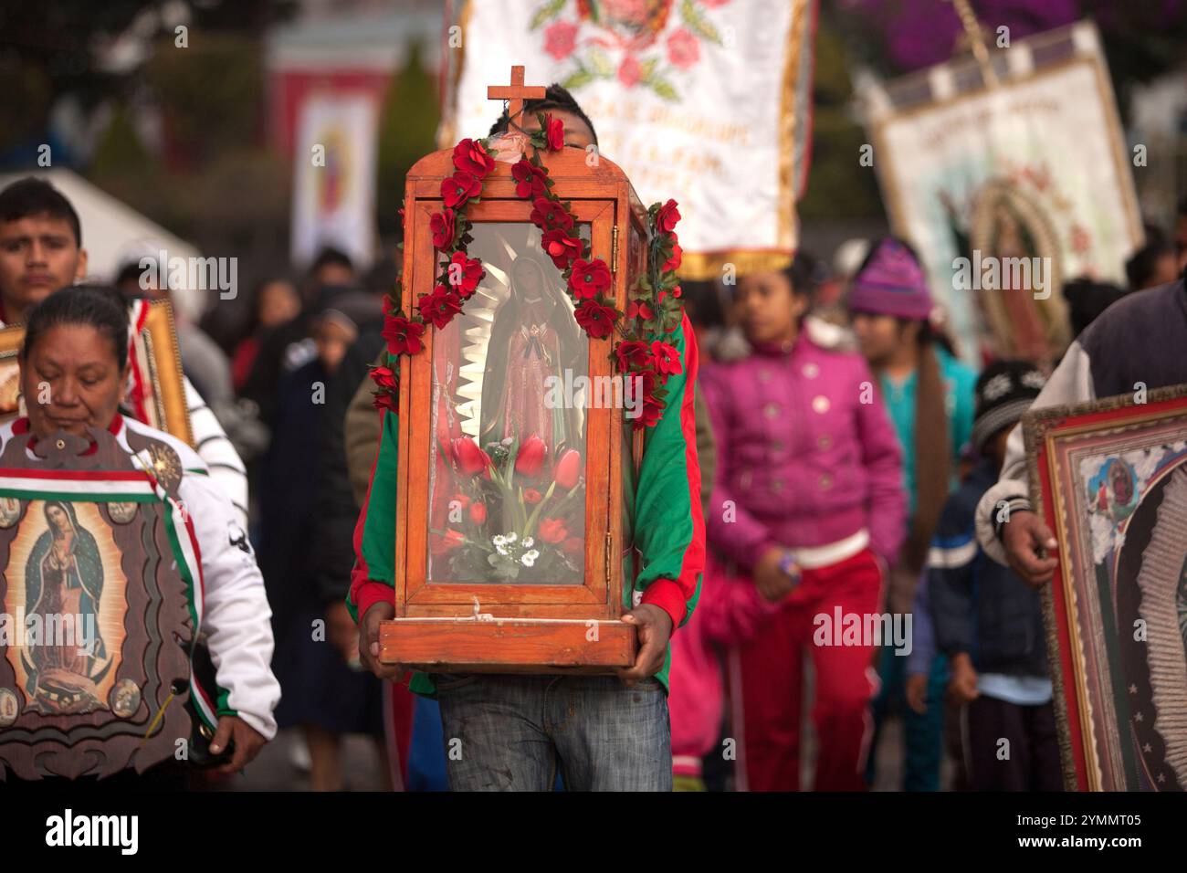 A pilgrim walks carrying images of the Virgin of Guadalupe during the ...