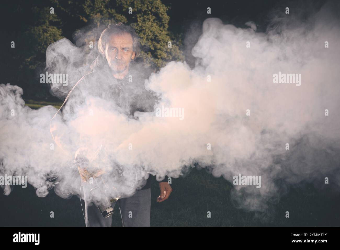 Older man uses two types of smoke machine generators on outdoor ...