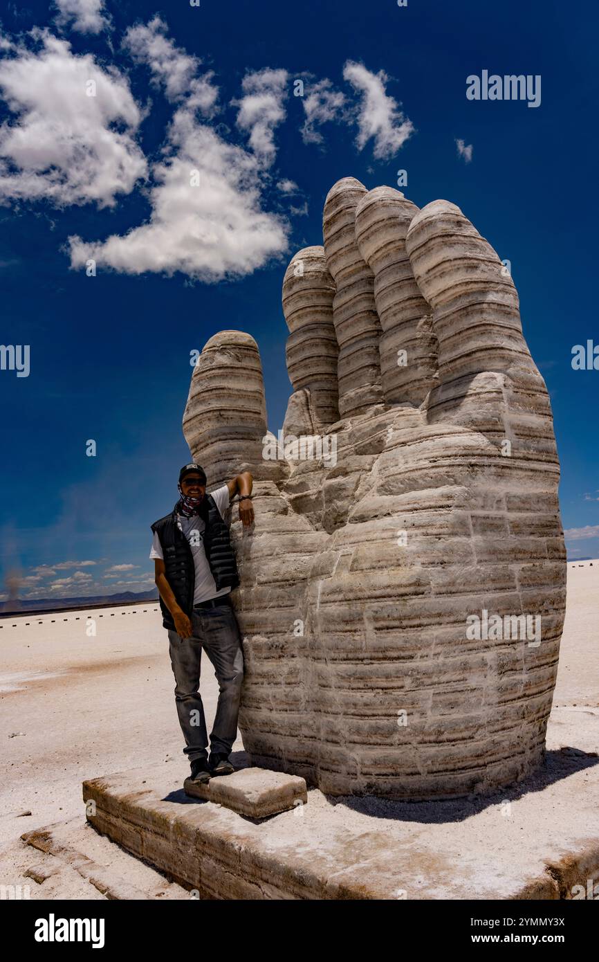 Tourist leaning on the hand of the desert, a famous sculpture in the ...