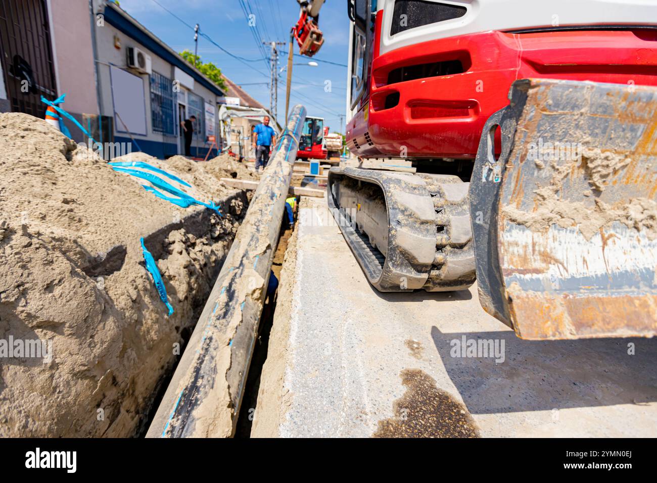 Small excavator with rubber crawler is standing next to the trench with ...