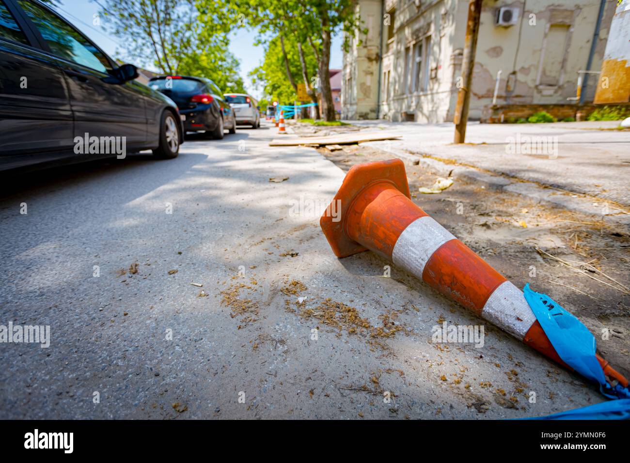 Fallen orange traffic cone with white fluorescent stripes is on the ...