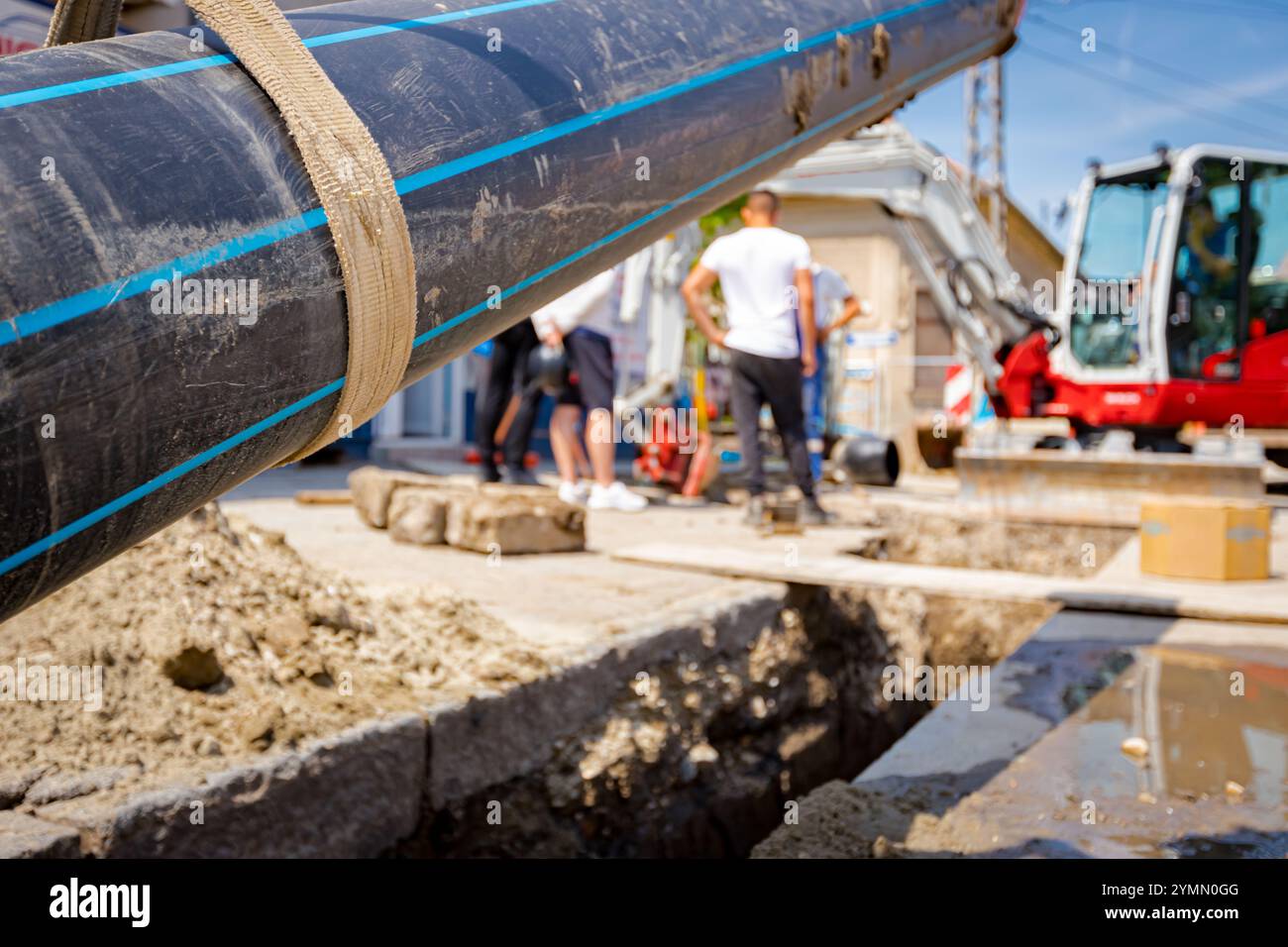 Small excavator with rubber crawler is standing next to the trench with ...