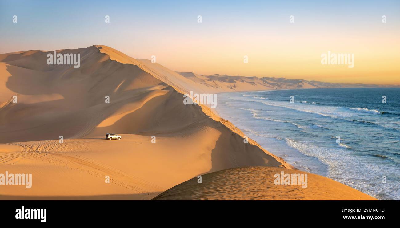 Car in the sand dunes and ocean view in Sandwich Harbour, Namib ...