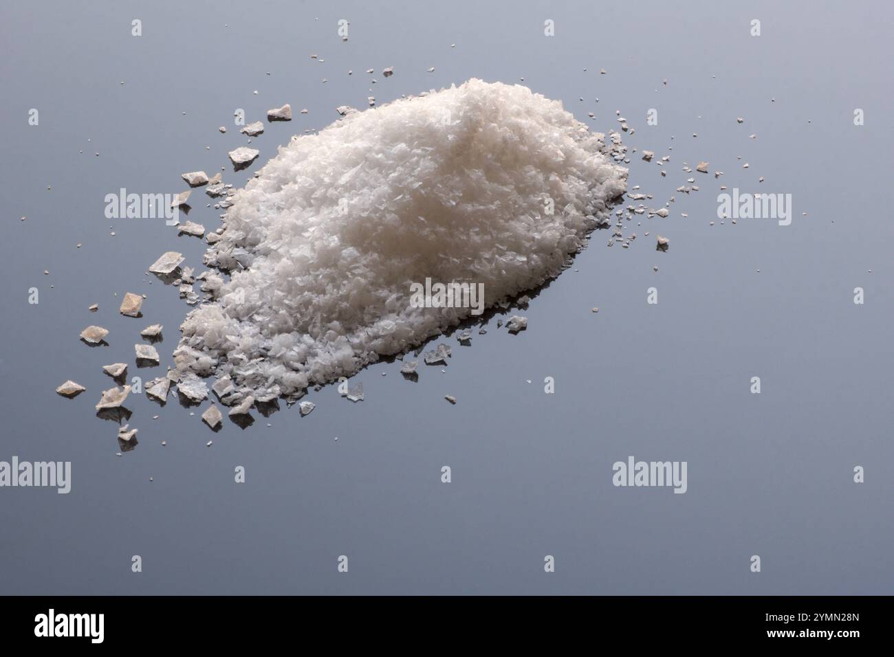 flakes of crisp maldon crystals salt on light blue reflective surface ...
