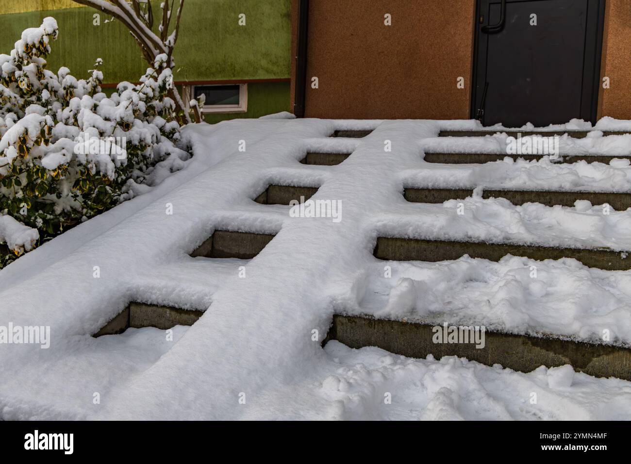 First snowfall, snow-covered stairs and wheelchair ramp leading to the ...