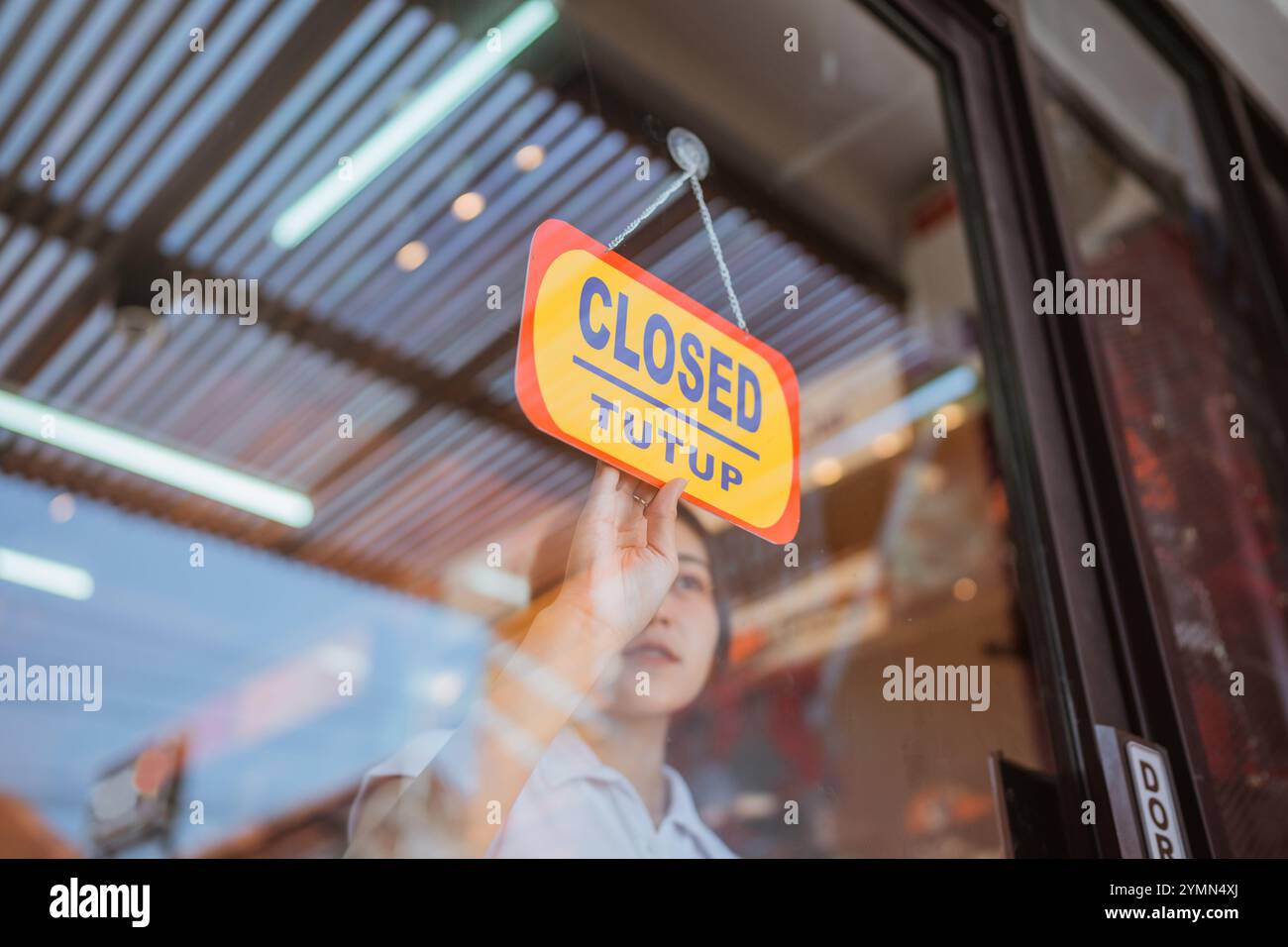 asian female employee flipping closed sign Stock Photo - Alamy