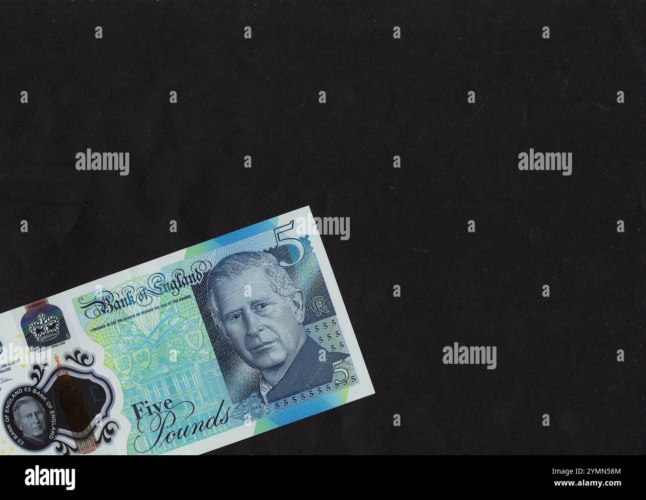 A King Charles III £5 banknote from the United Kingdom on a black ...