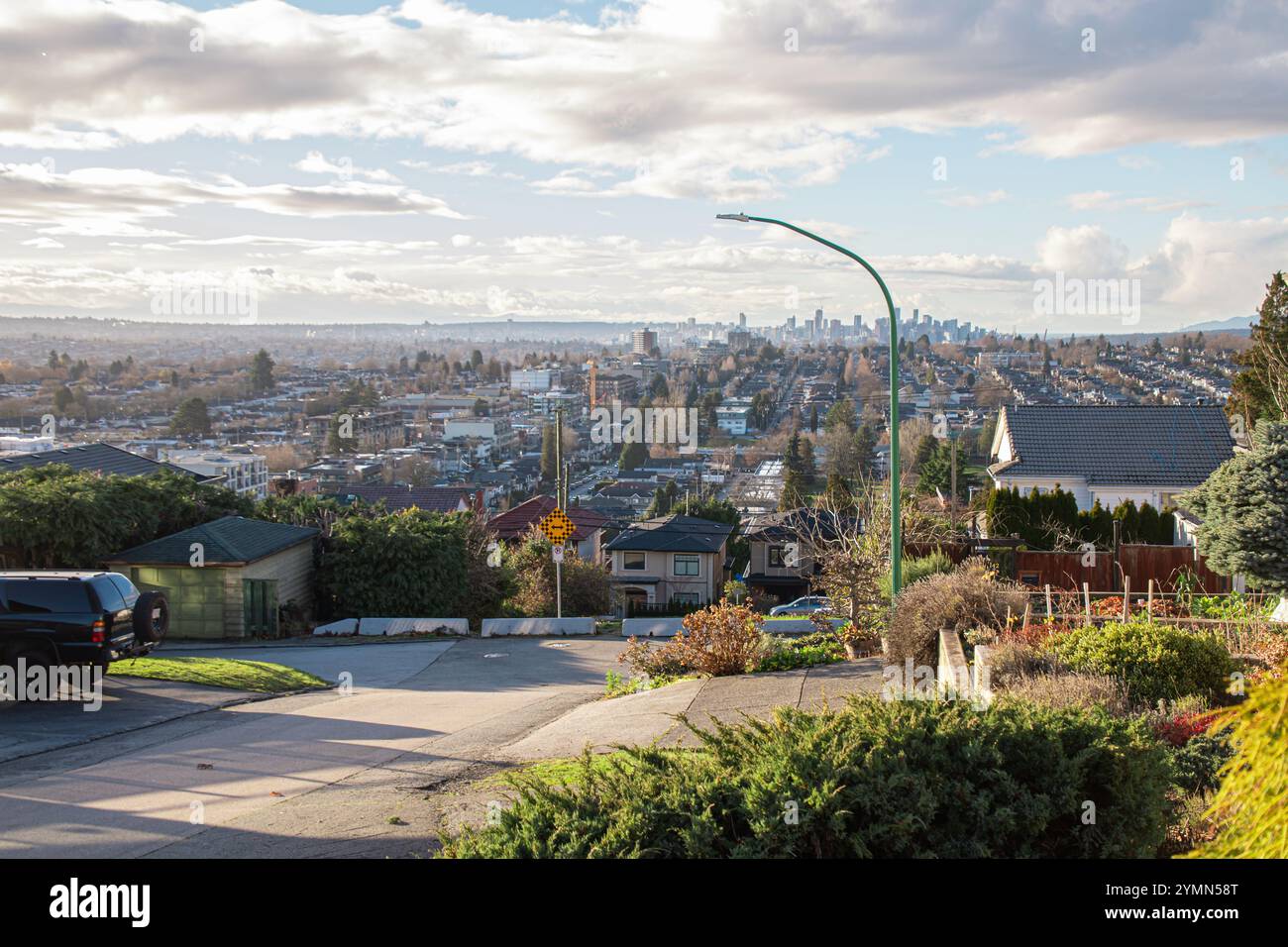 A quiet suburban street in Burnaby Heights with houses and parked cars ...