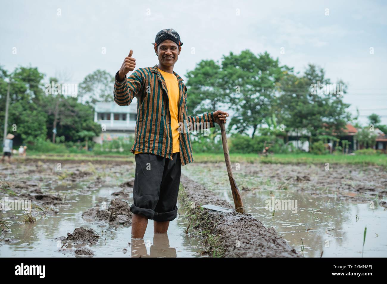 A Young Farmer Joyfully Celebrating His Success in a Waterlogged Rice ...