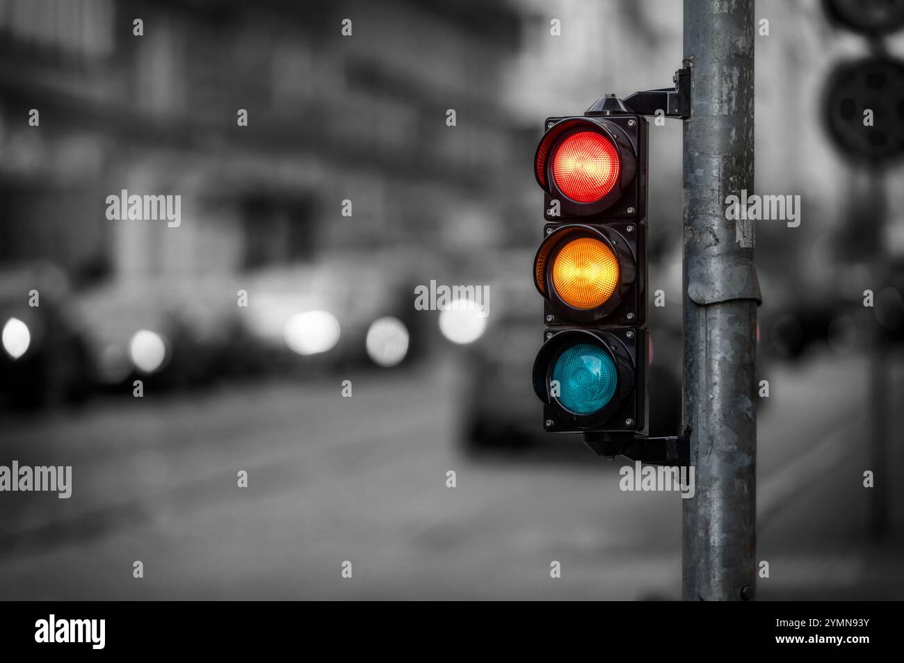 A traffic signal at an intersection shows red, yellow, and green lights ...