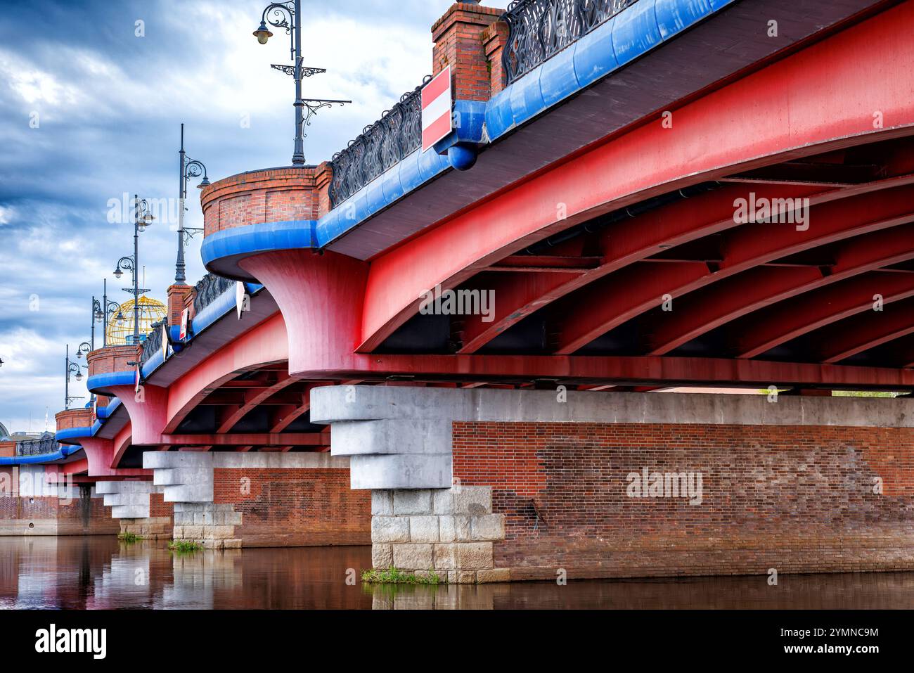 Beautiful, urban, stone bridge over the river, painted in red and blue ...
