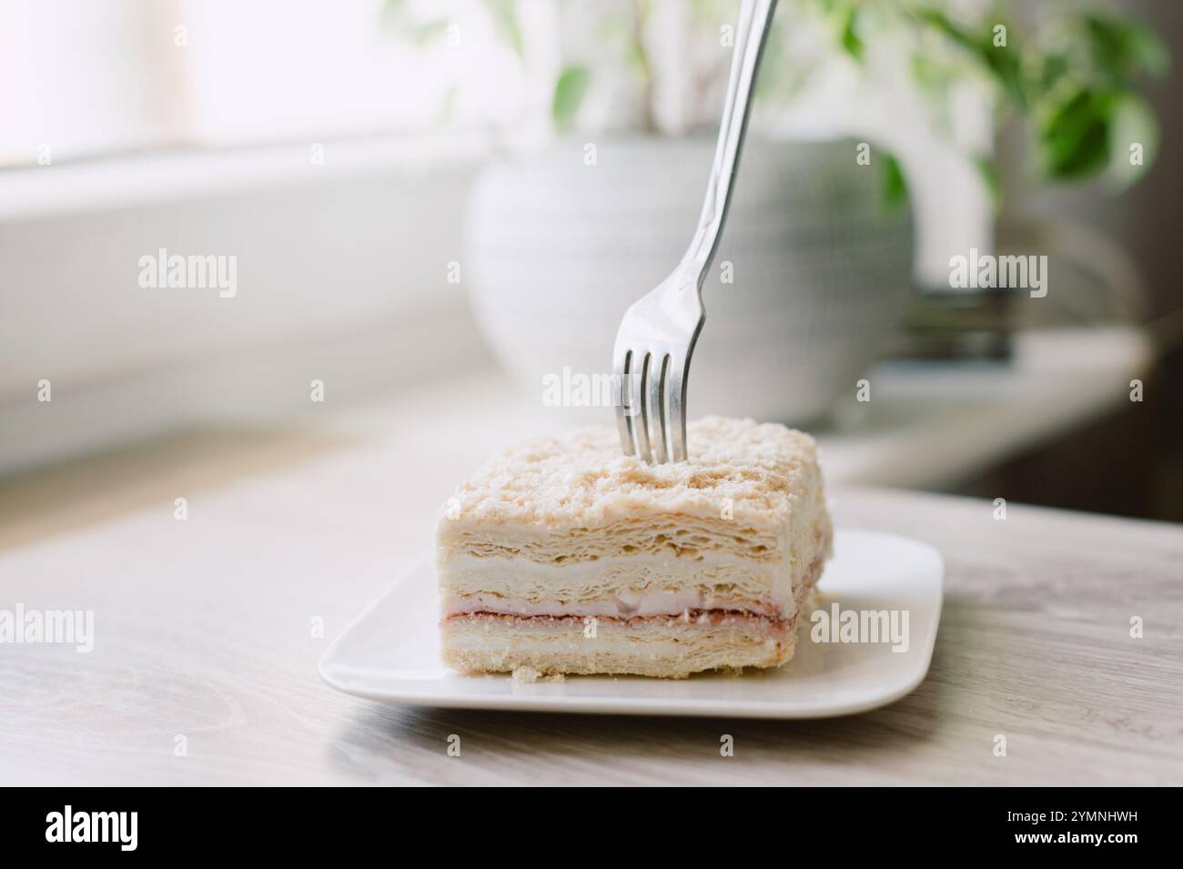 A fork is being used to eat a piece of cake. The cake is on a plate ...