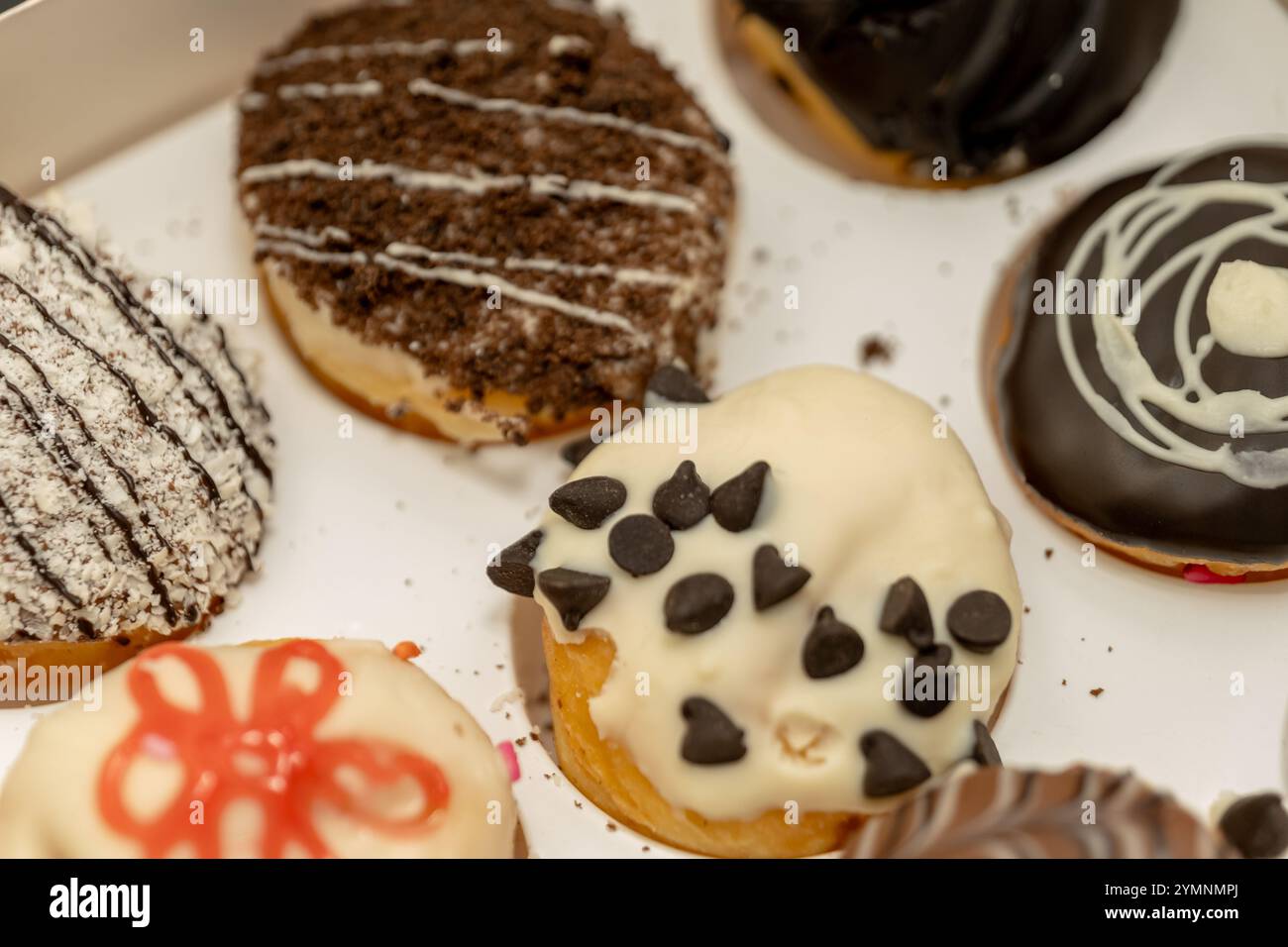 Assorted mini donuts with colorful toppings and icing in a white box ...