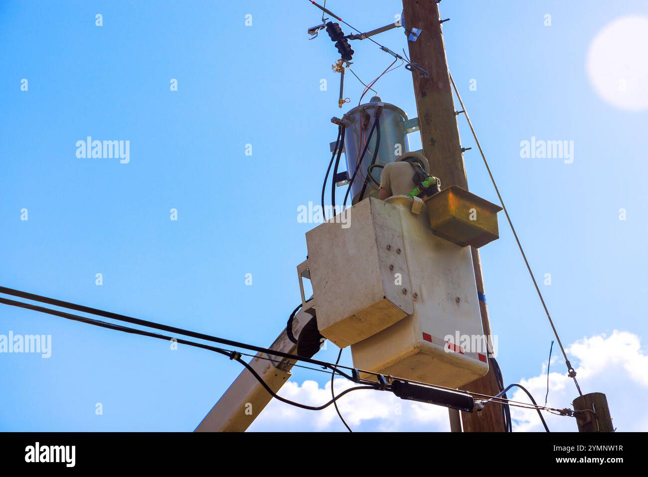 Technician works safely from bucket lift to install service electrical ...