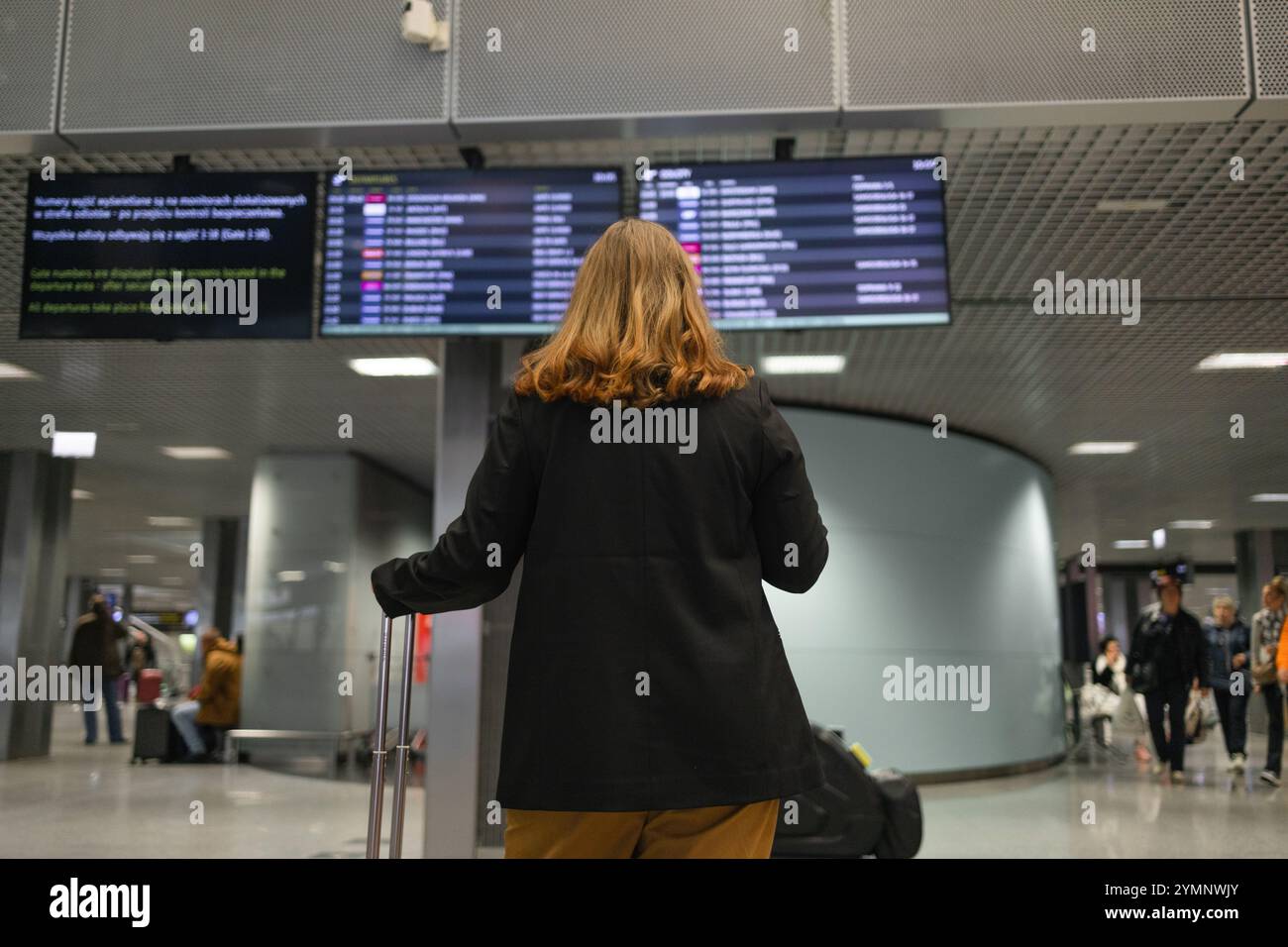 Young 30s woman in international airport, using mobile smartphone and checking flight, flight ...