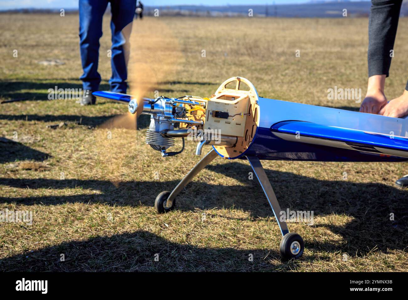 A man holds a working model airplane in a bright blue color by the ...