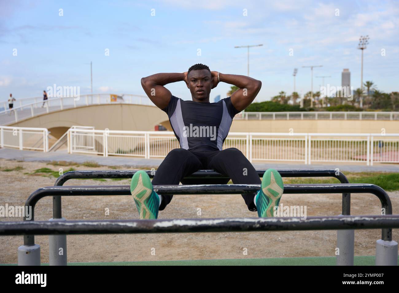 Black athlete performing calisthenics sit-ups on parallel bars outdoors ...