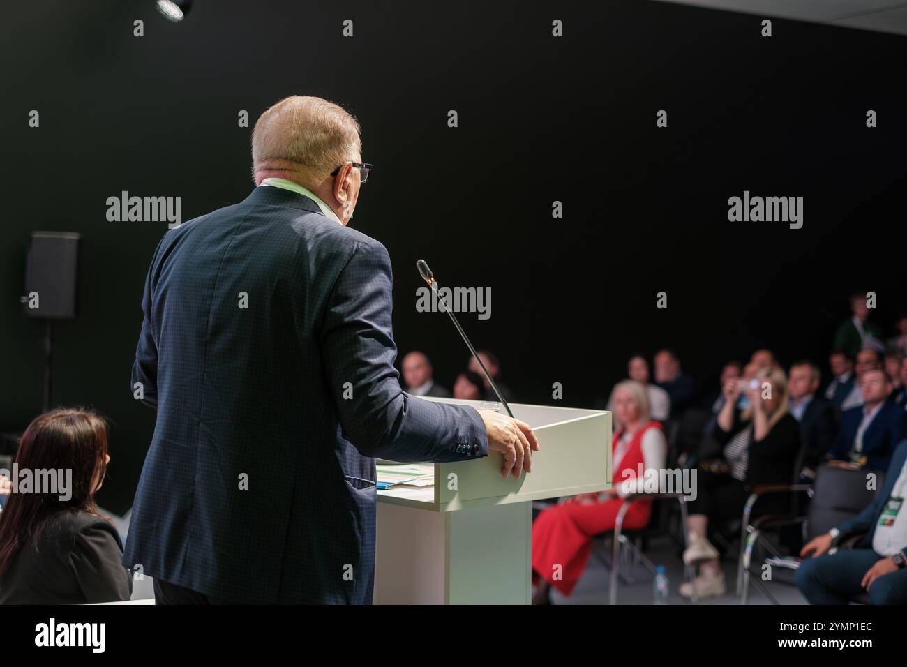 Senior man speaking at business conference with attentive audience ...