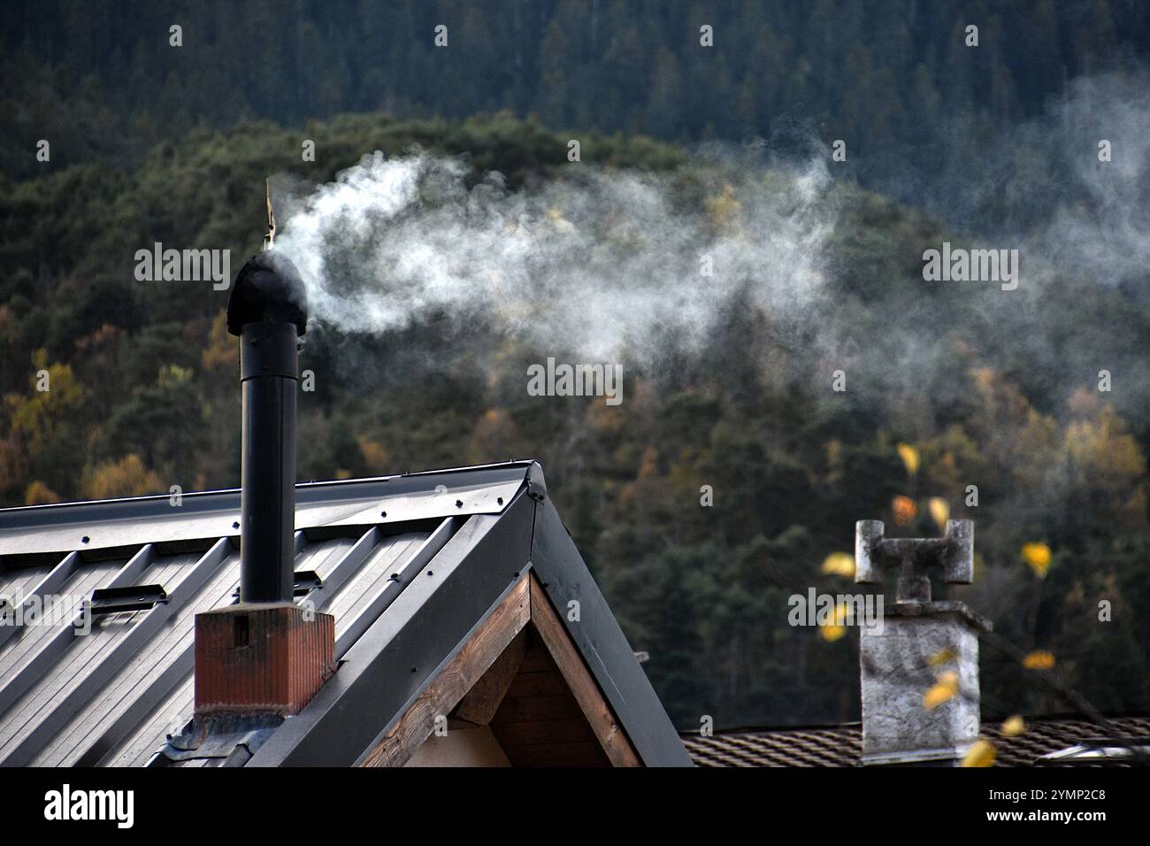 Smoke billows from a chimney on the roof, from a village house in La ...
