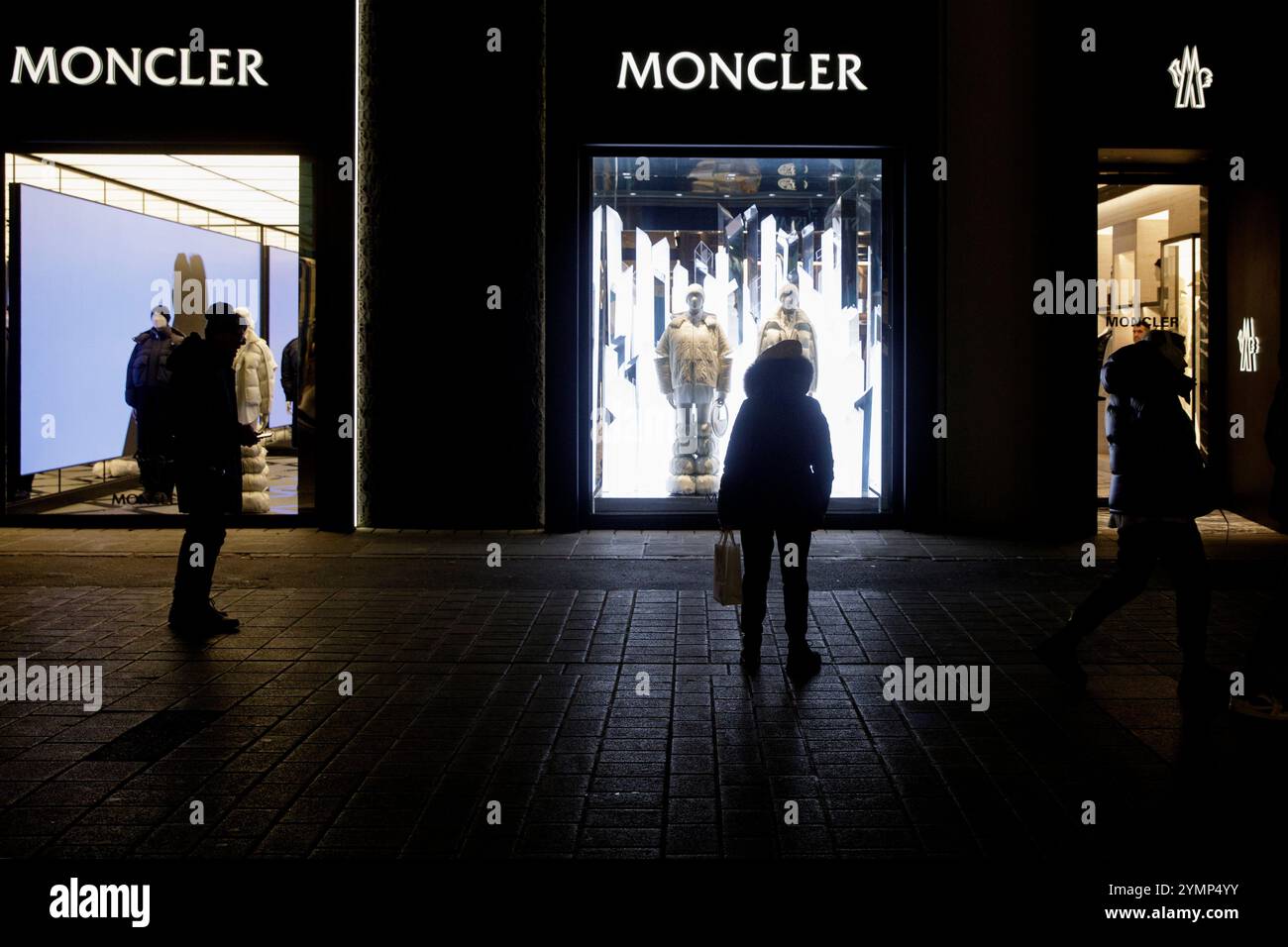 Passerby stands in front of the display of a shop of the Moncler ...