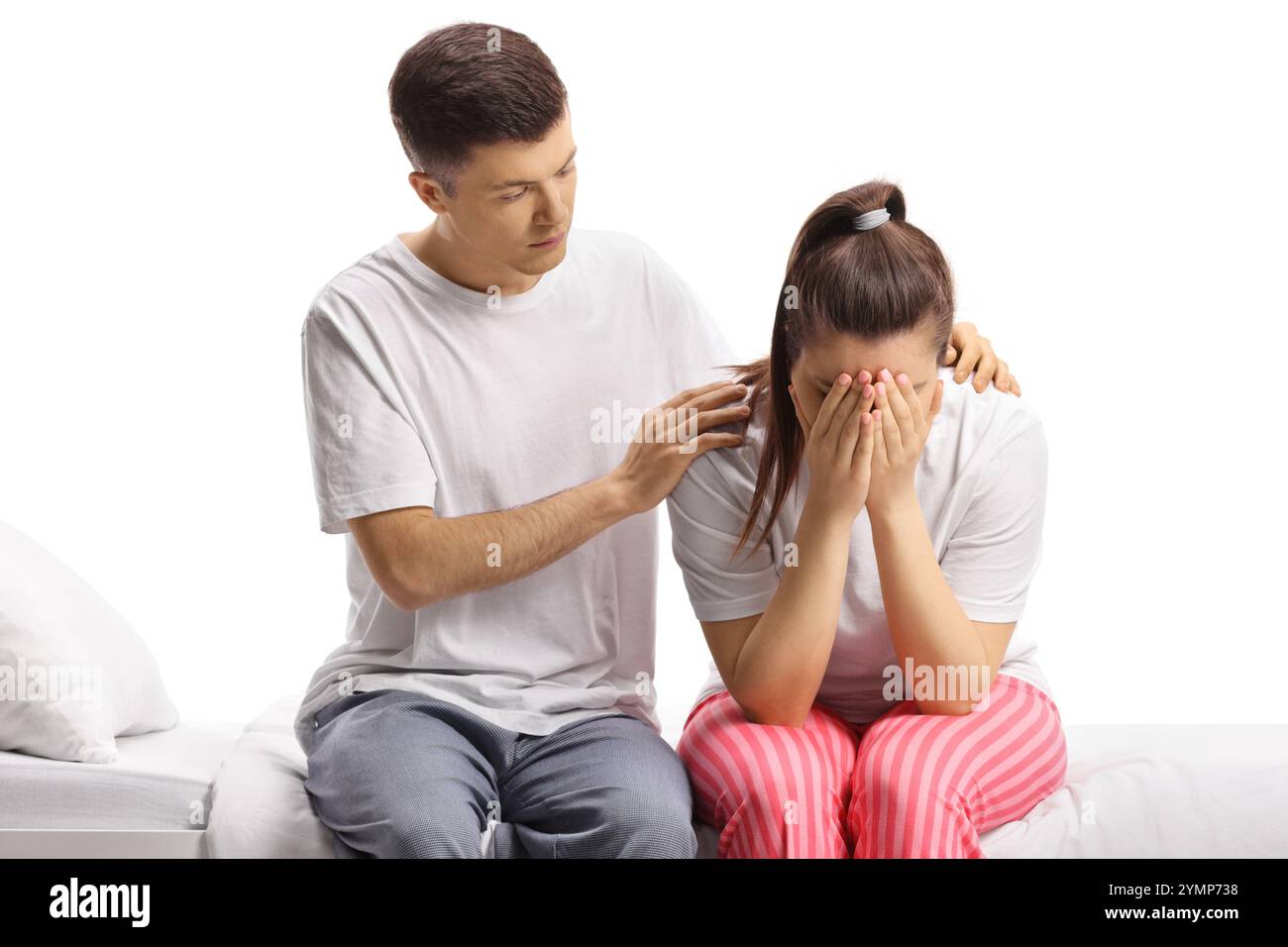 Sad female in pajamas sitting on a bed and guy comforting her isolated ...