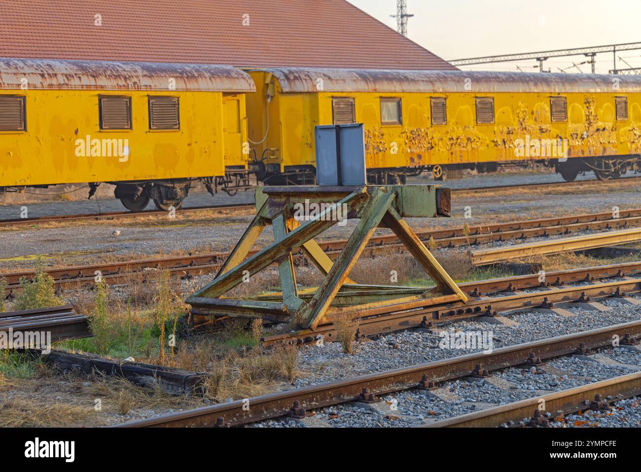 Metal Bumper Railroad Buffer Stop at Tracks and Old Yellow Train Wagon ...