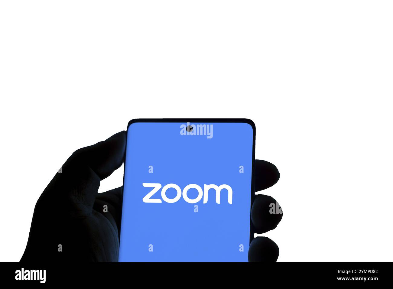 Zoom App logo on smartphone screen while Zoom meeting in the background ...