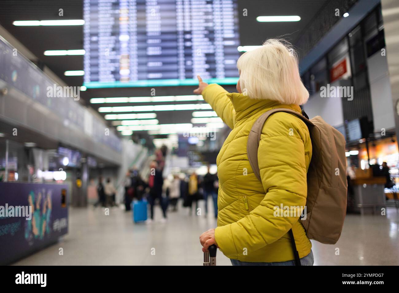 Caucasian senior woman passengers with suitcase using mobile phone booking hotel during waiting ...