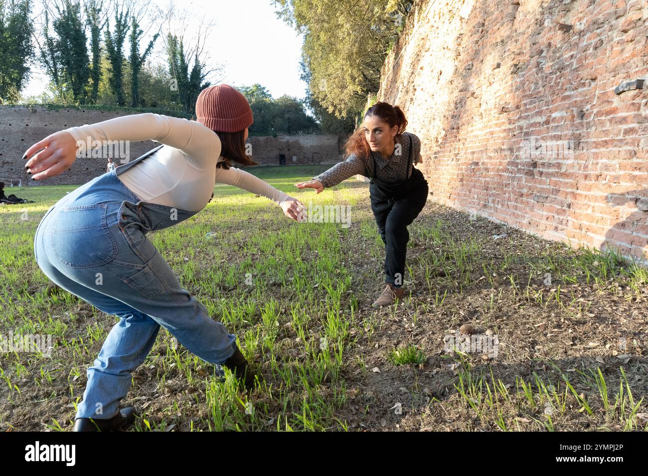 Two dancers performing a modern dance piece in a park, reaching towards ...