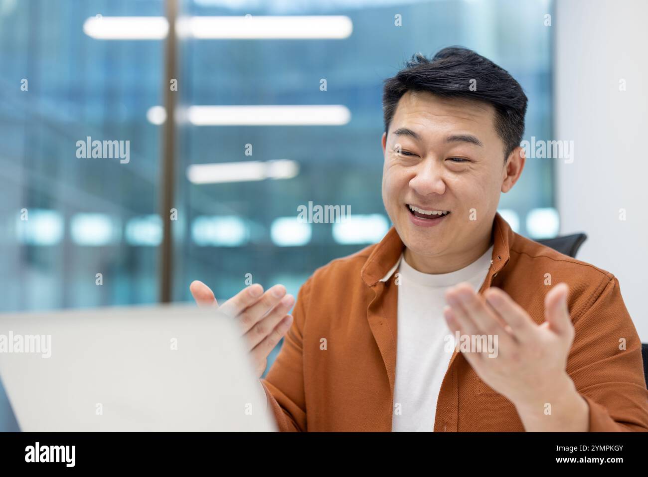 Asian man businessman engaged in video call in office. He appears happy ...