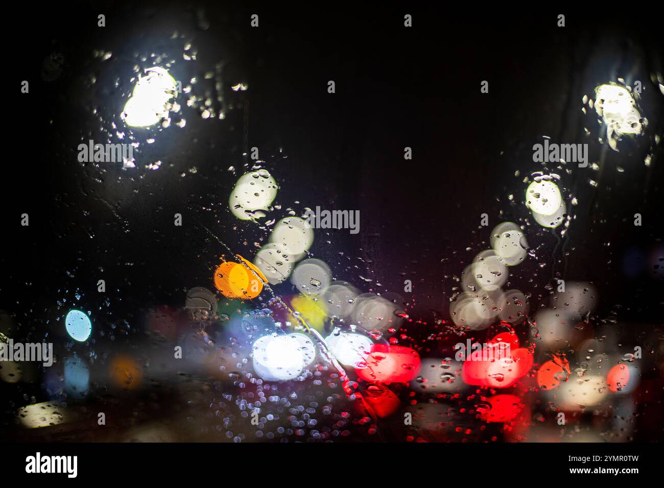 reflections of red brake lights from a car windshield in the rain in a ...
