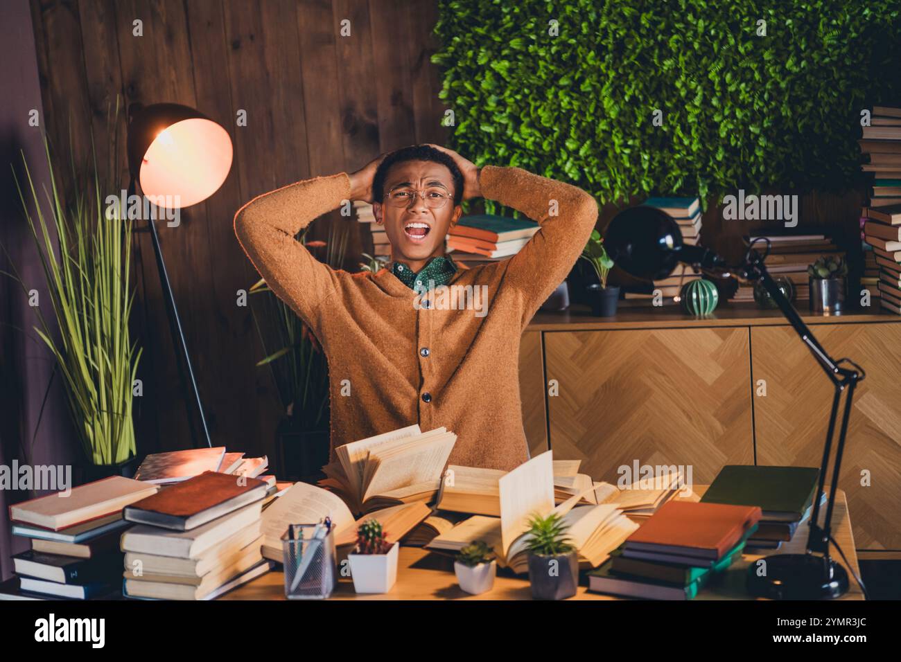 Young student overwhelmed with study materials in home setting, wearing ...