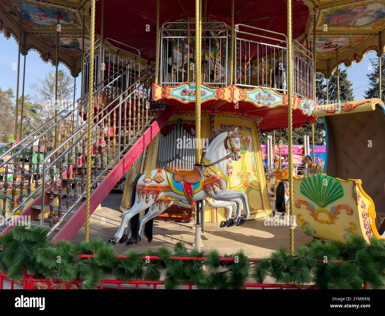 A colorful carousel with decorated horses and a two-tier structure ...