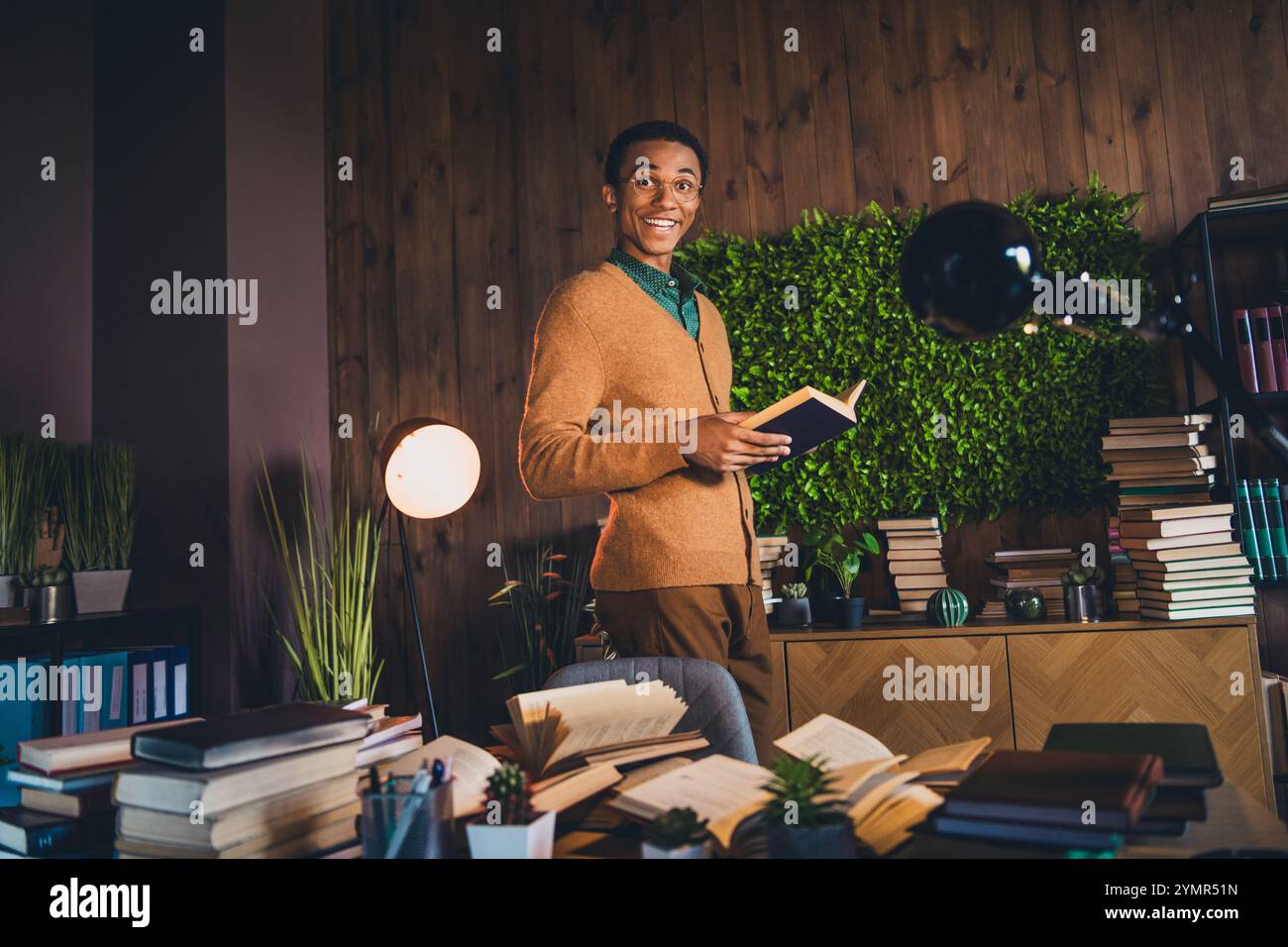 Young student in a cozy home office, smiling while studying in a warm ...