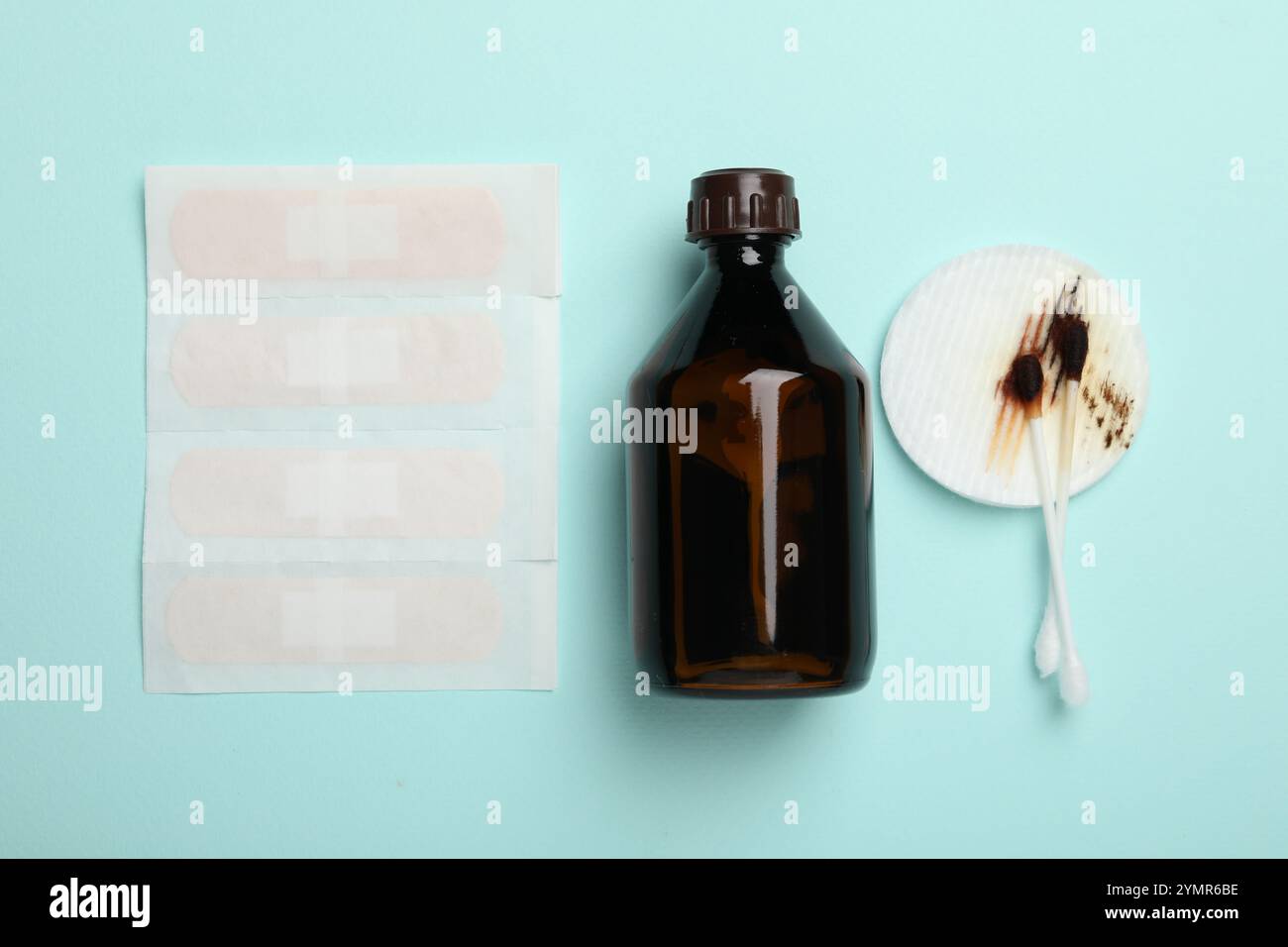 Topical iodine and other first aid kit components on light blue ...