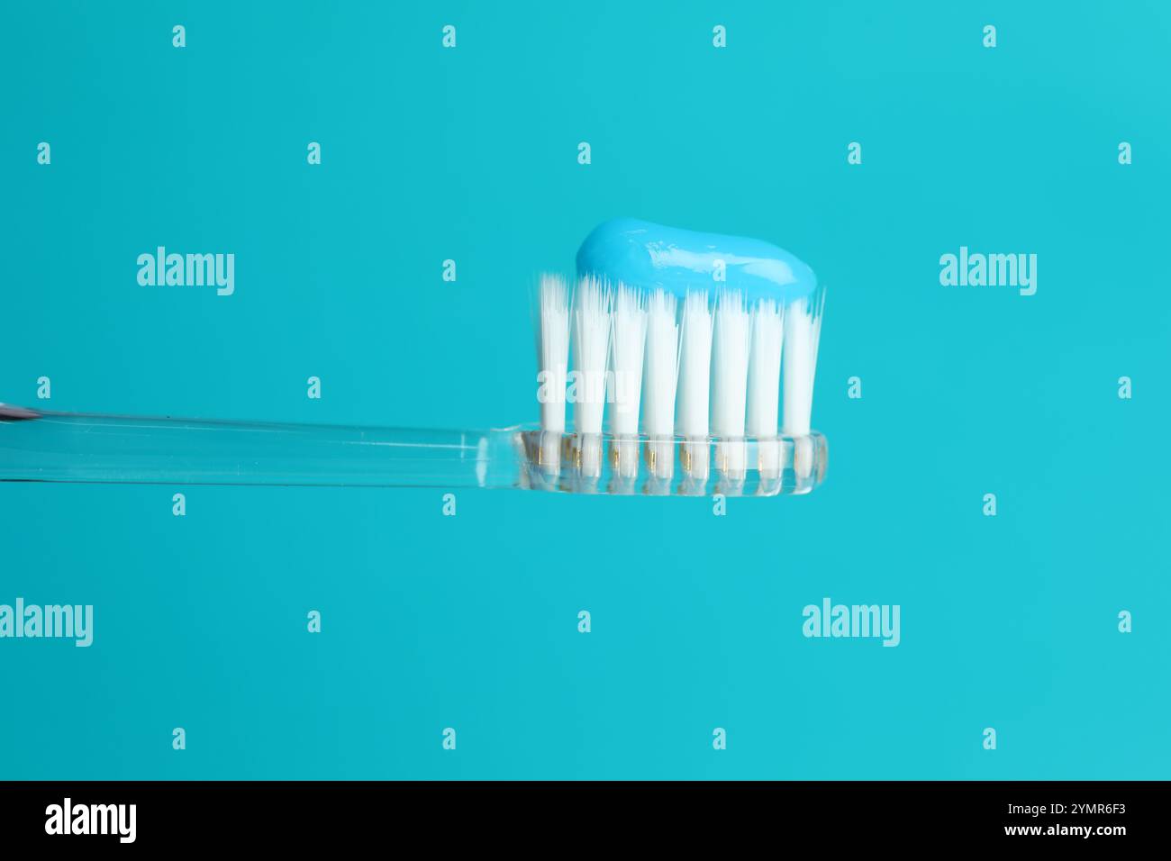 Toothbrush with toothpaste in air on light blue background, closeup ...