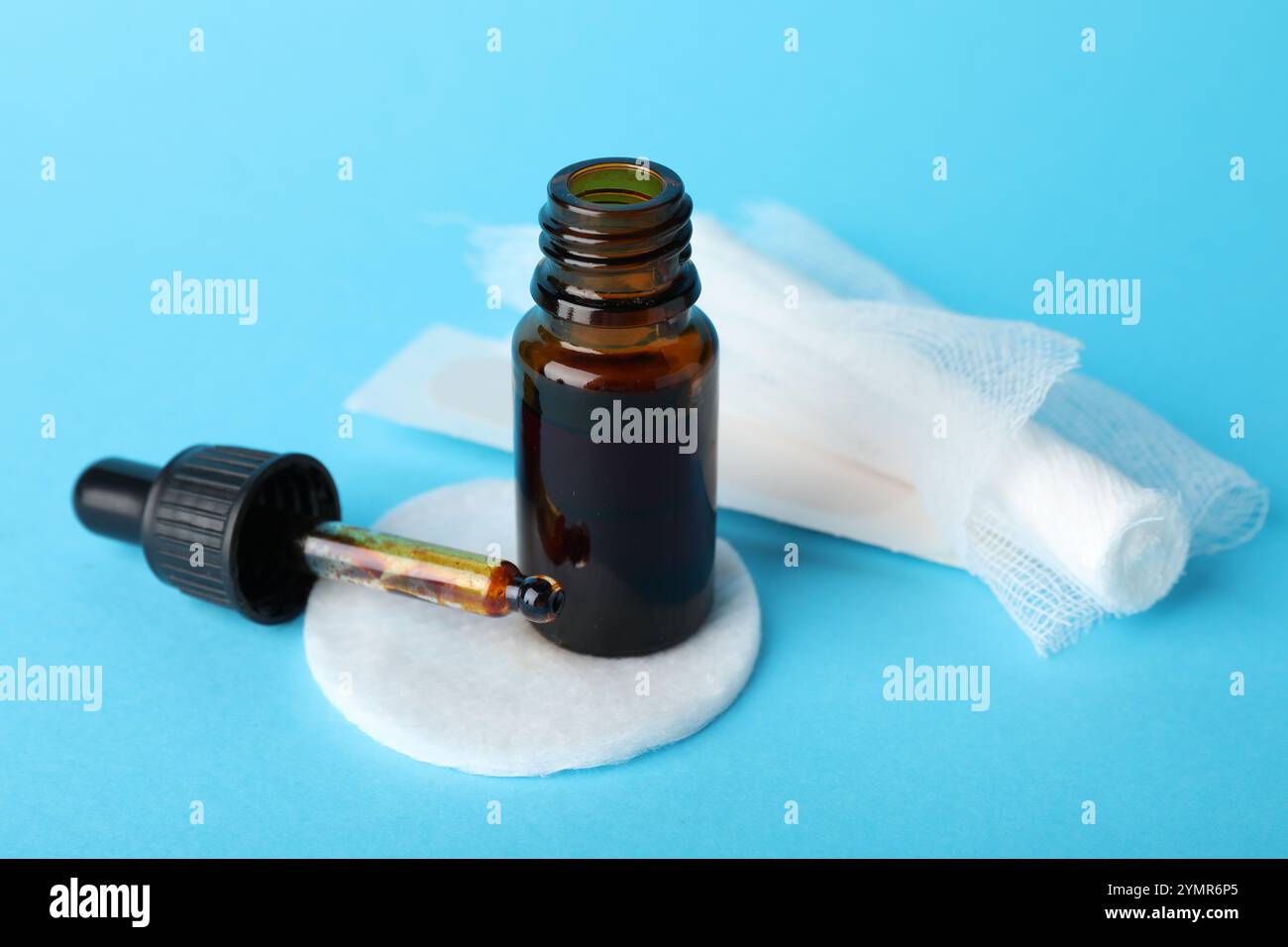 Topical iodine, cotton pad and bandage on light blue background ...