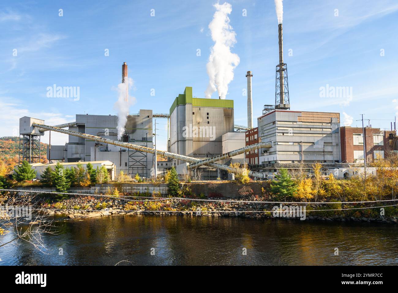 Manufacturing plant with tall smokestacks belching white smoke on the ...
