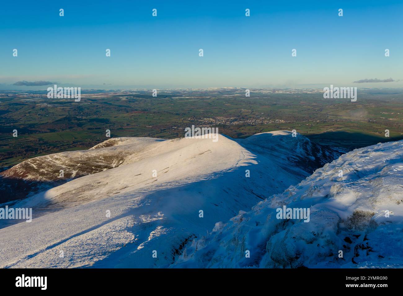 Snow covered mountain ridge with green, lowland areas behind Stock ...