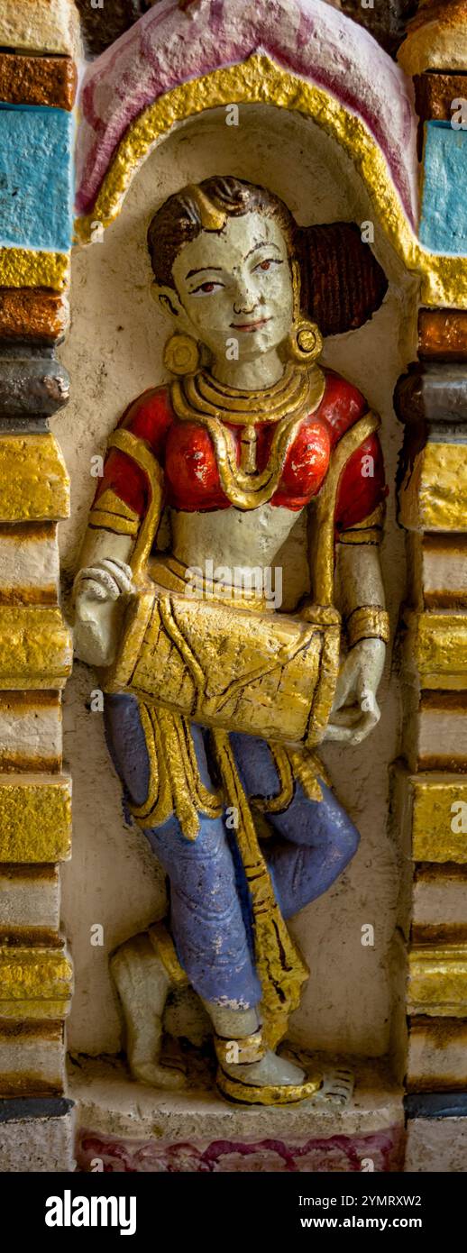 Vibrant painted bas relief sculpture depicting a female dancer holding ...