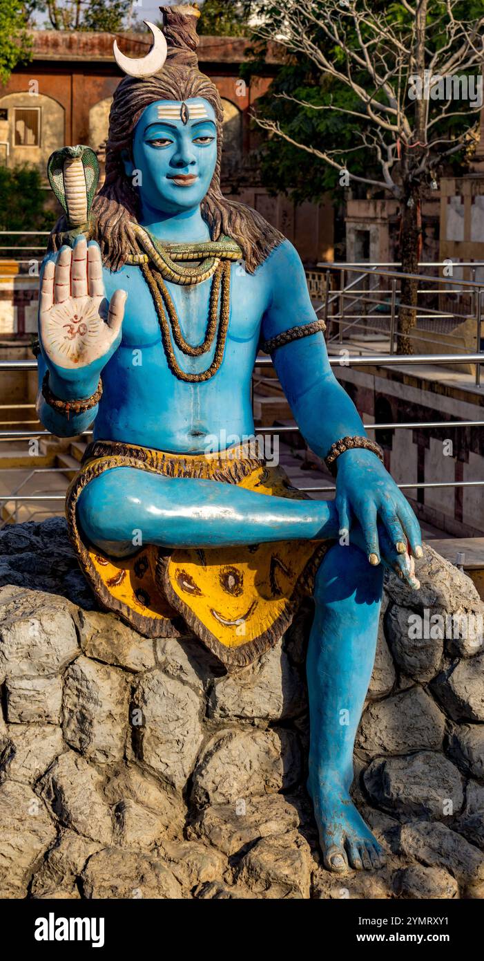 Colorful statue of the hindu god shiva sitting in virasana yoga pose ...