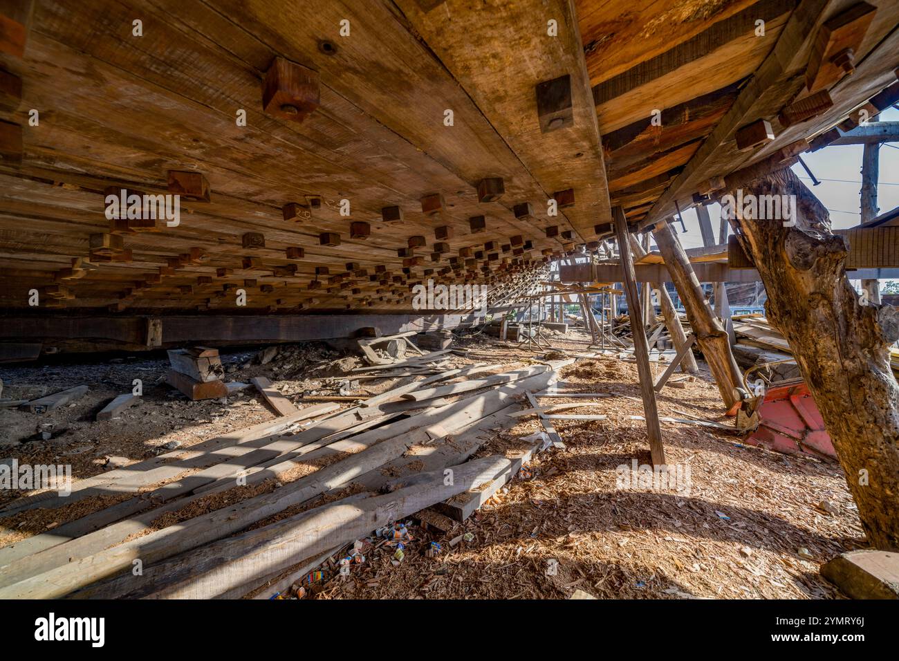 Sunlight illuminates the underside of a wooden boat under construction ...