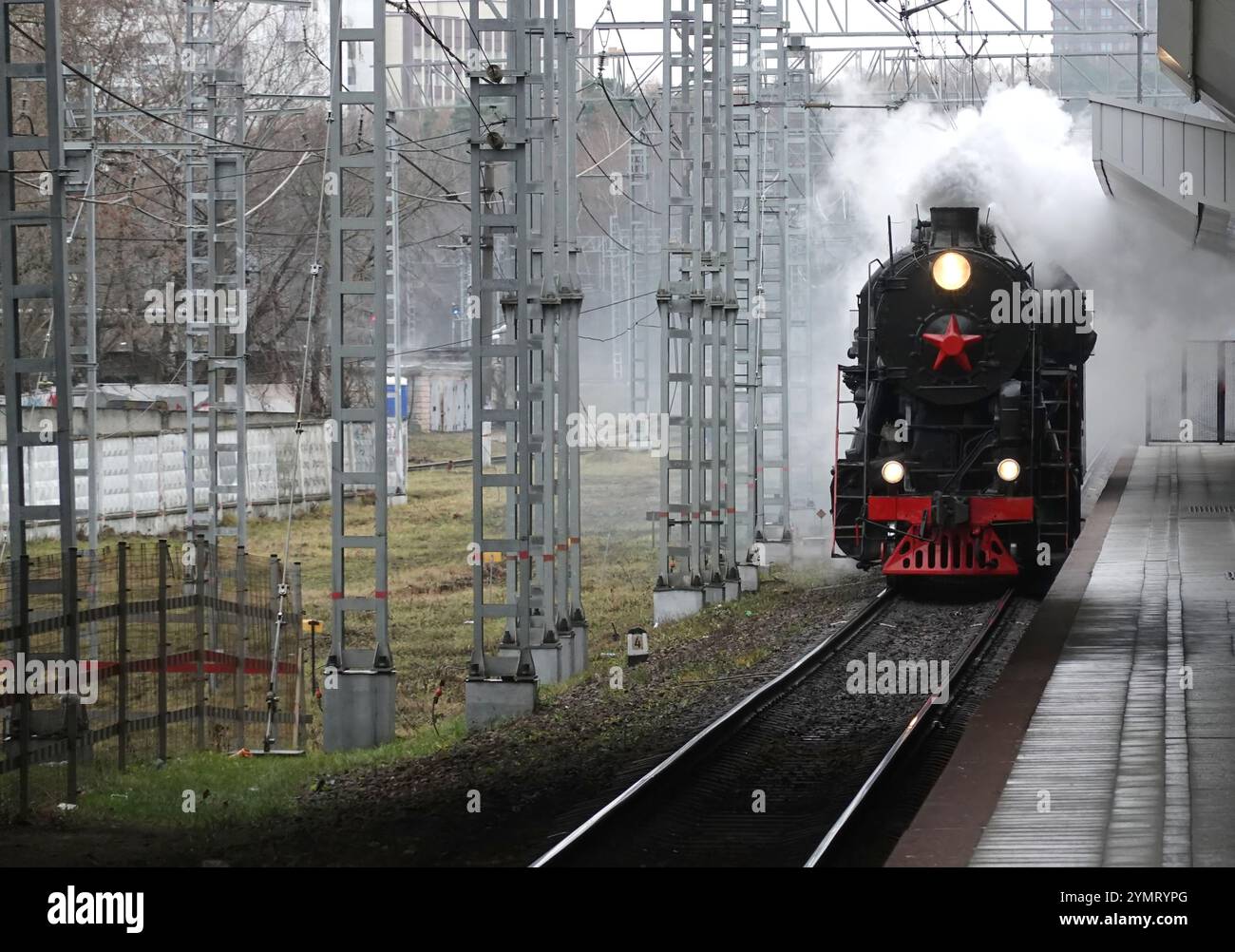Industrial landscape with old black steam locomotive with red star on ...