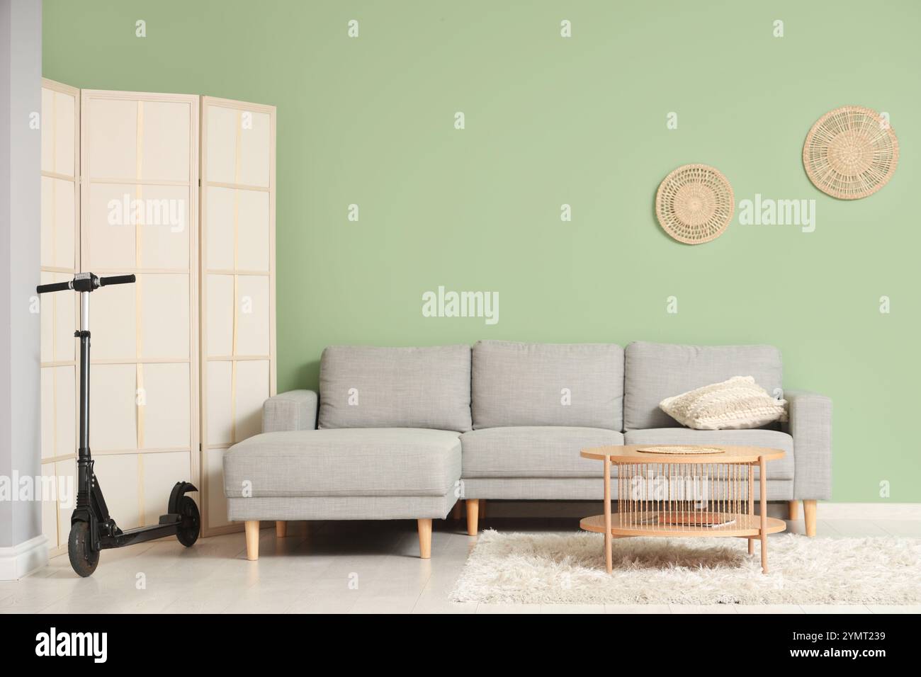 Interior of living room with electric scooter, sofa and folding screen ...