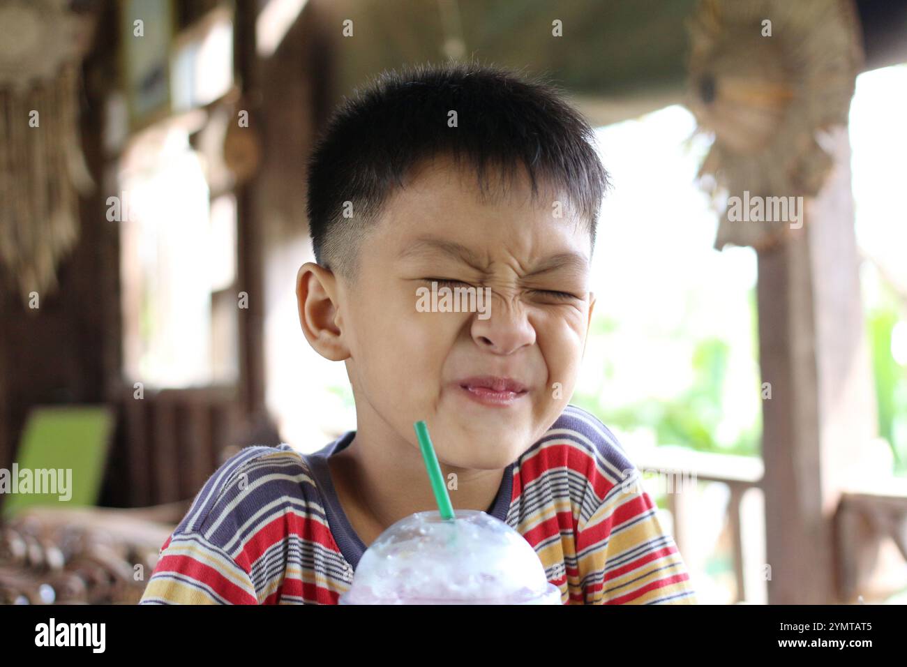 A joyful child with a playful expression enjoys a colorful drink in a ...